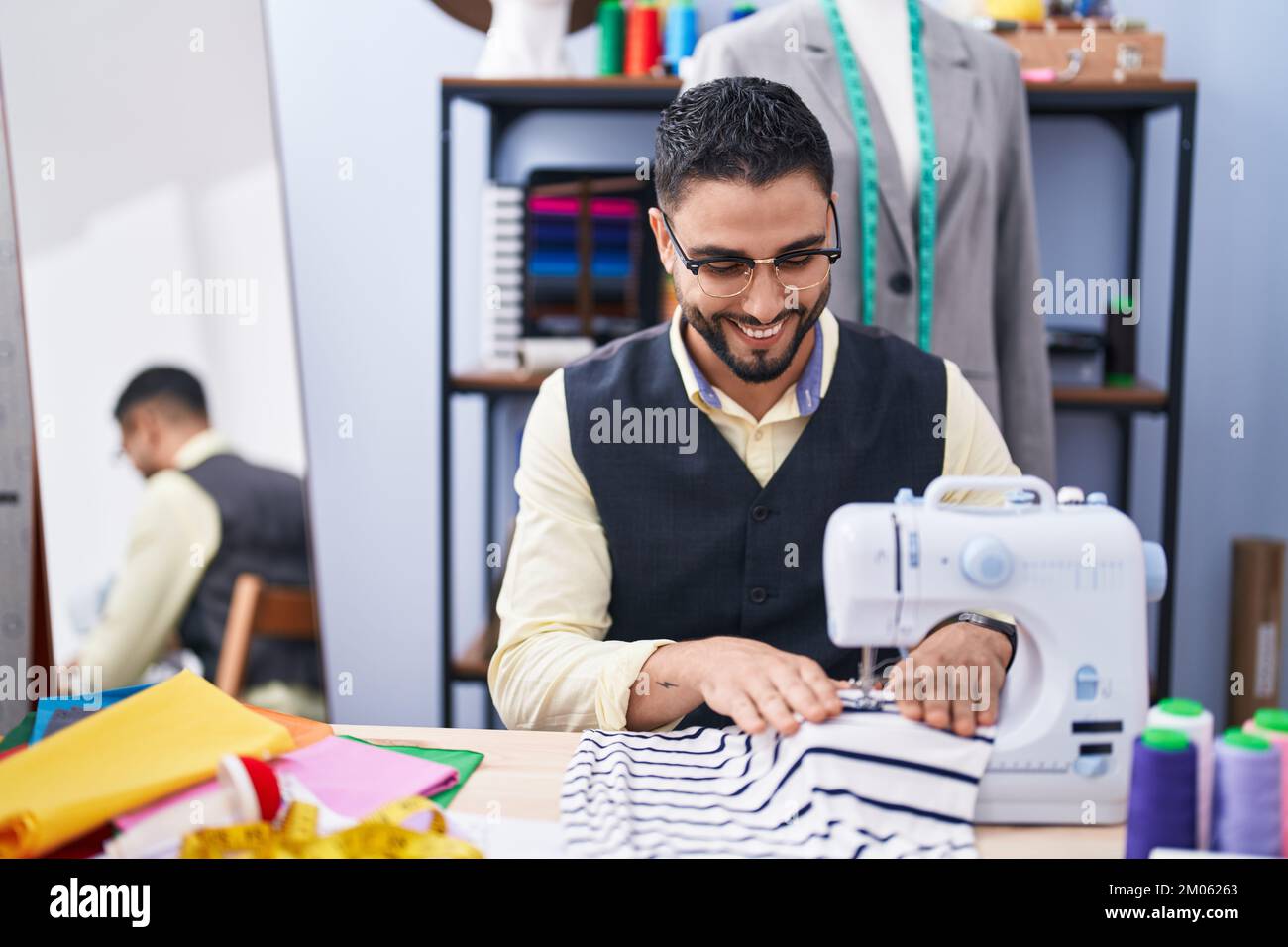 Young arab man tailor smiling confident using sewing machine at ...