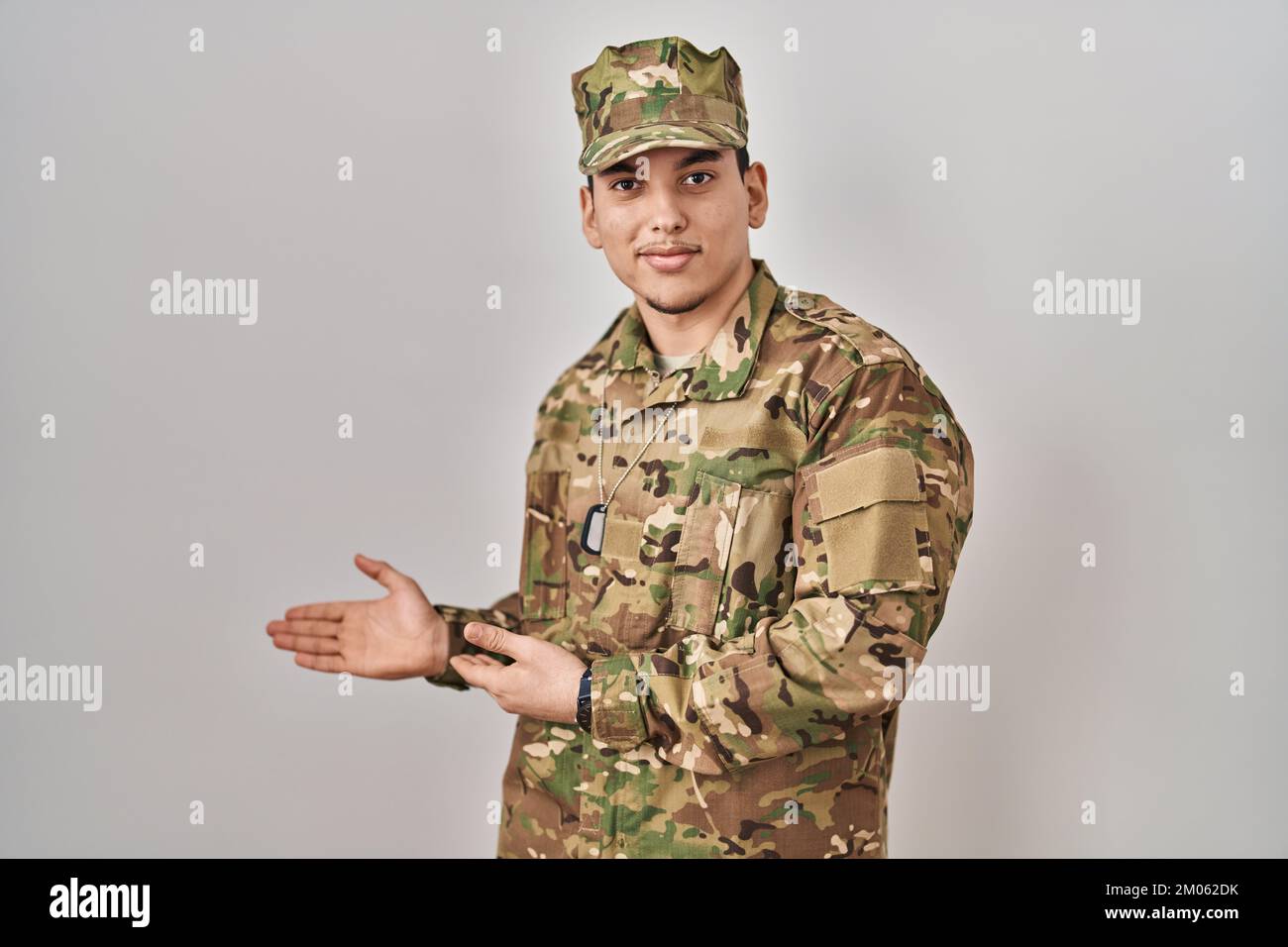 Young arab man wearing camouflage army uniform inviting to enter ...
