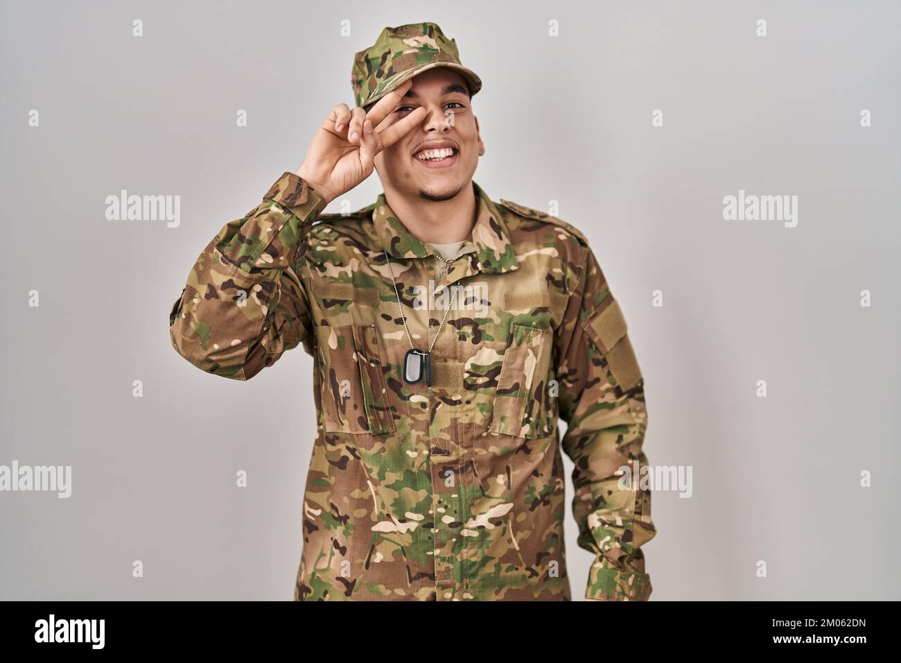 Young arab man wearing camouflage army uniform doing peace symbol with ...