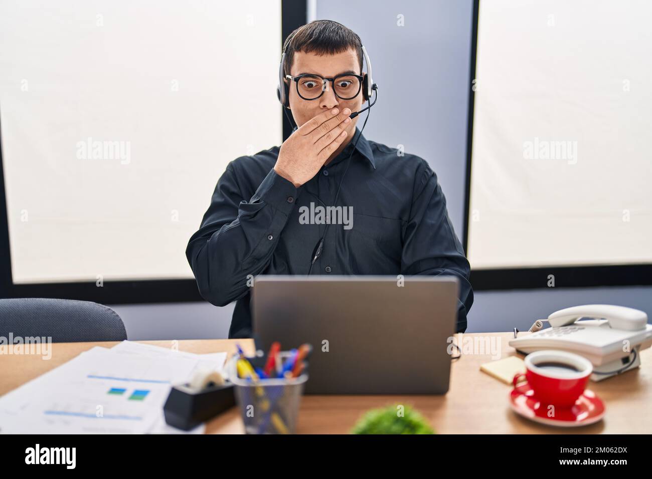 Young arab man wearing call center agent headset covering mouth with ...