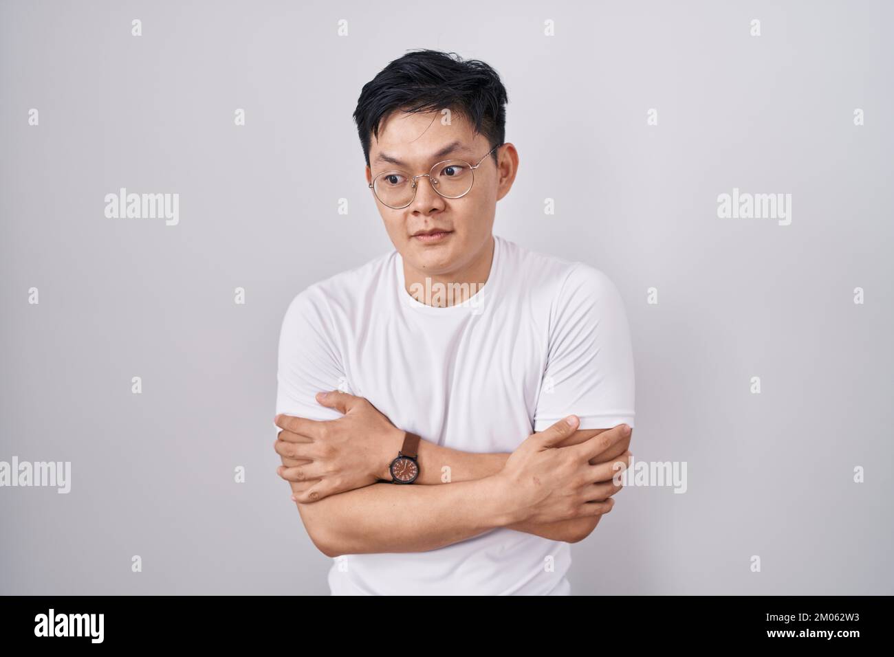 Young asian man standing over white background shaking and freezing for ...