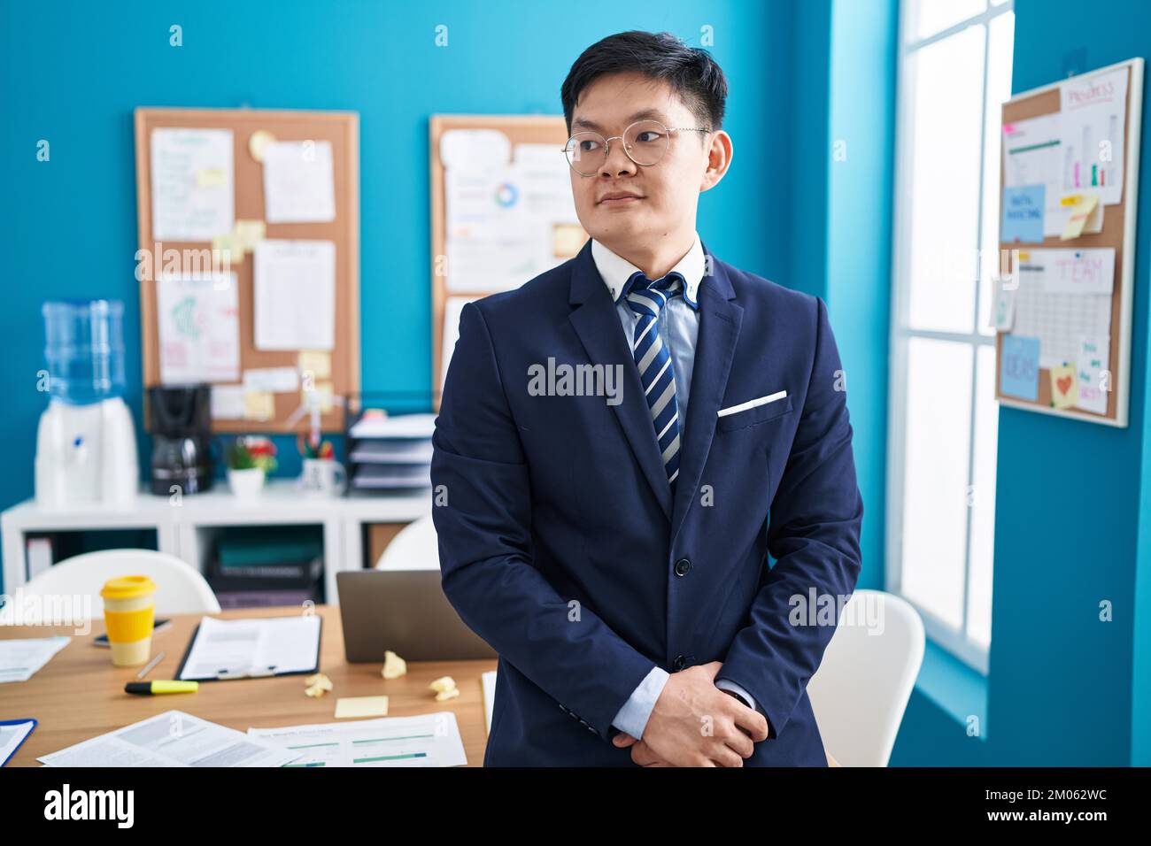 Young chinese man business worker standing with relaxed expression at ...