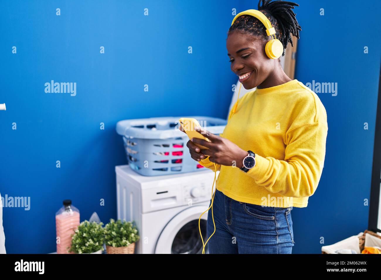 African american woman liatening to music waiting for washing machine ...