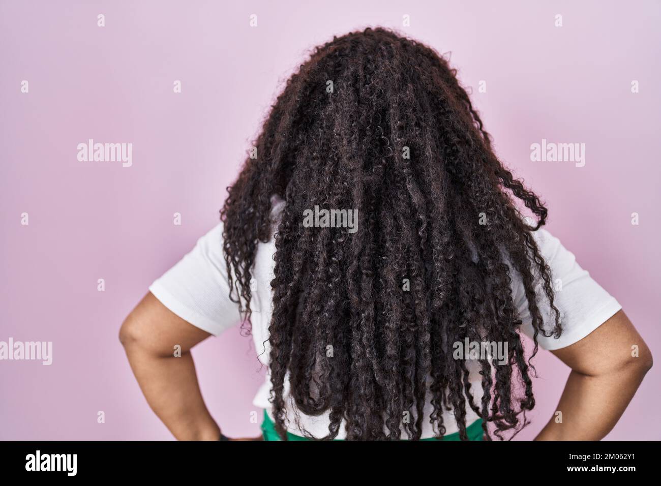 Plus size hispanic woman standing over pink background standing ...