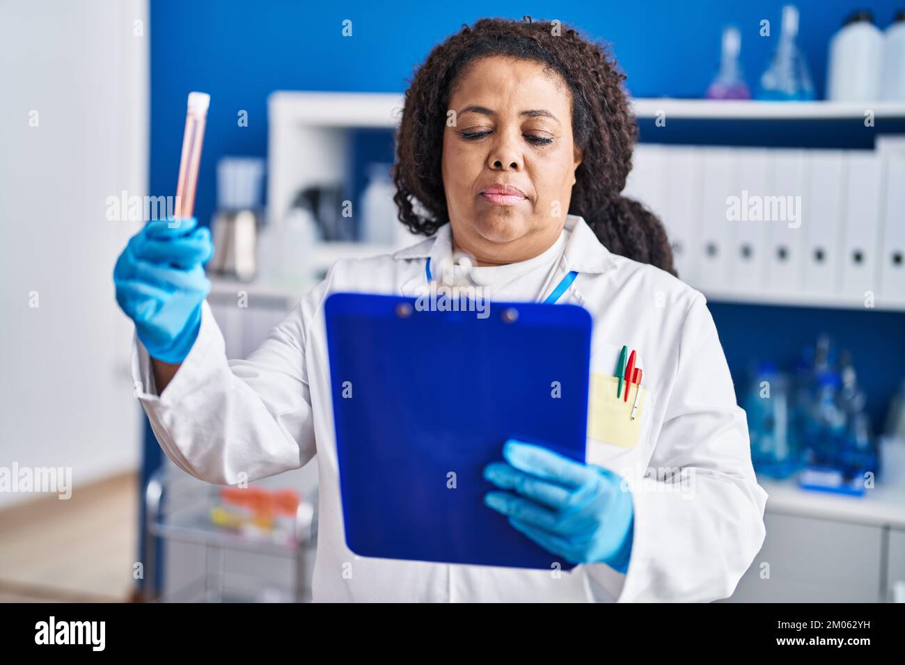 African american woman scientist reading document holding test tube at ...