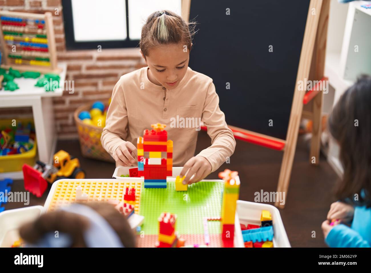 Adorable toddler playing with construction blocks sitting on table at ...
