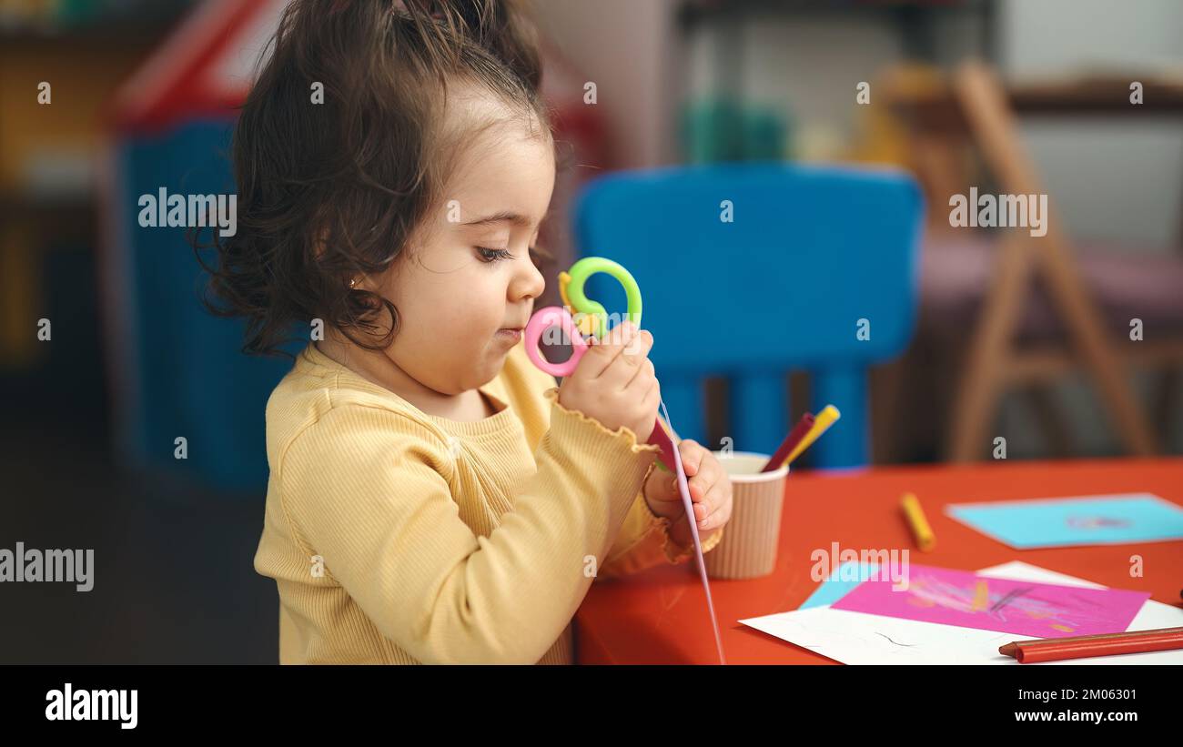 Adorable hispanic girl student cutting paper at kindergarten Stock ...