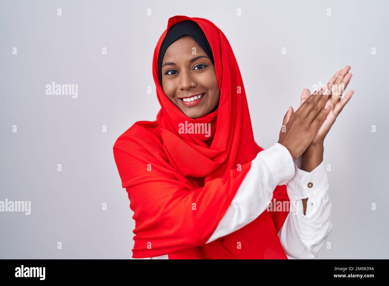 Young arab woman wearing traditional islamic hijab scarf clapping and ...