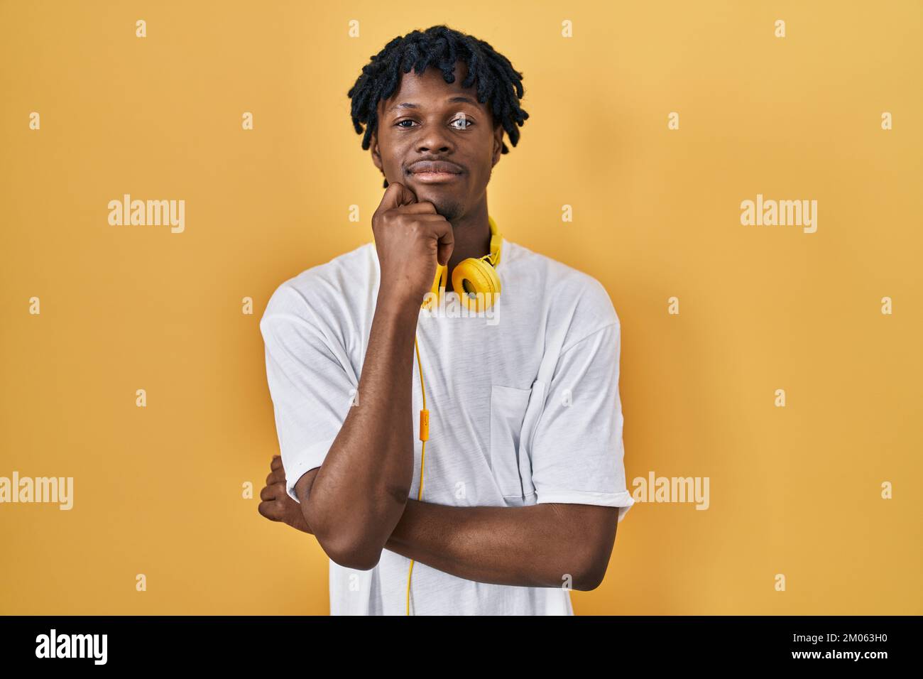 Young african man with dreadlocks standing over yellow background with ...