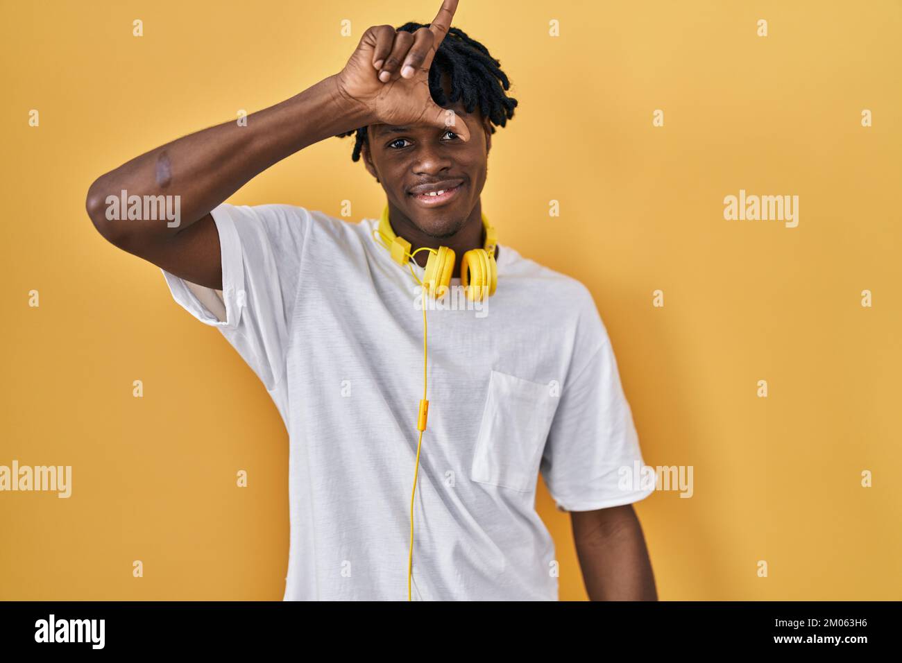 Young african man with dreadlocks standing over yellow background ...
