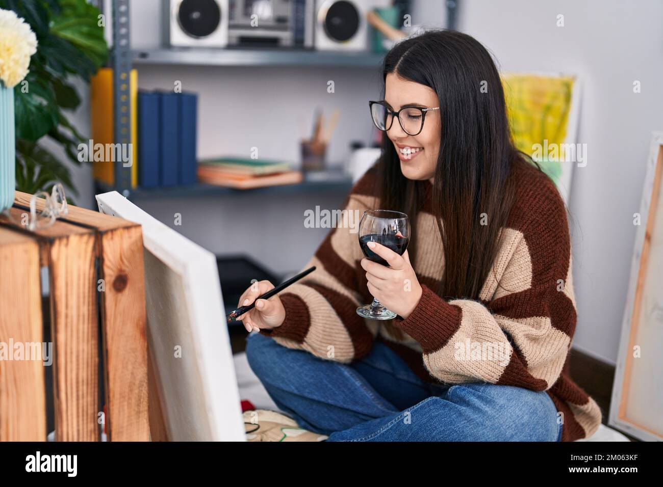 Young hispanic woman artist drinking wine drawing at art studio Stock ...