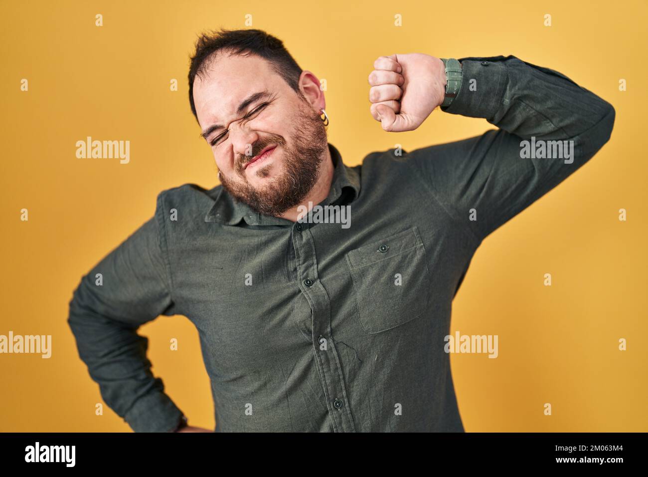 Plus size hispanic man with beard standing over yellow background ...