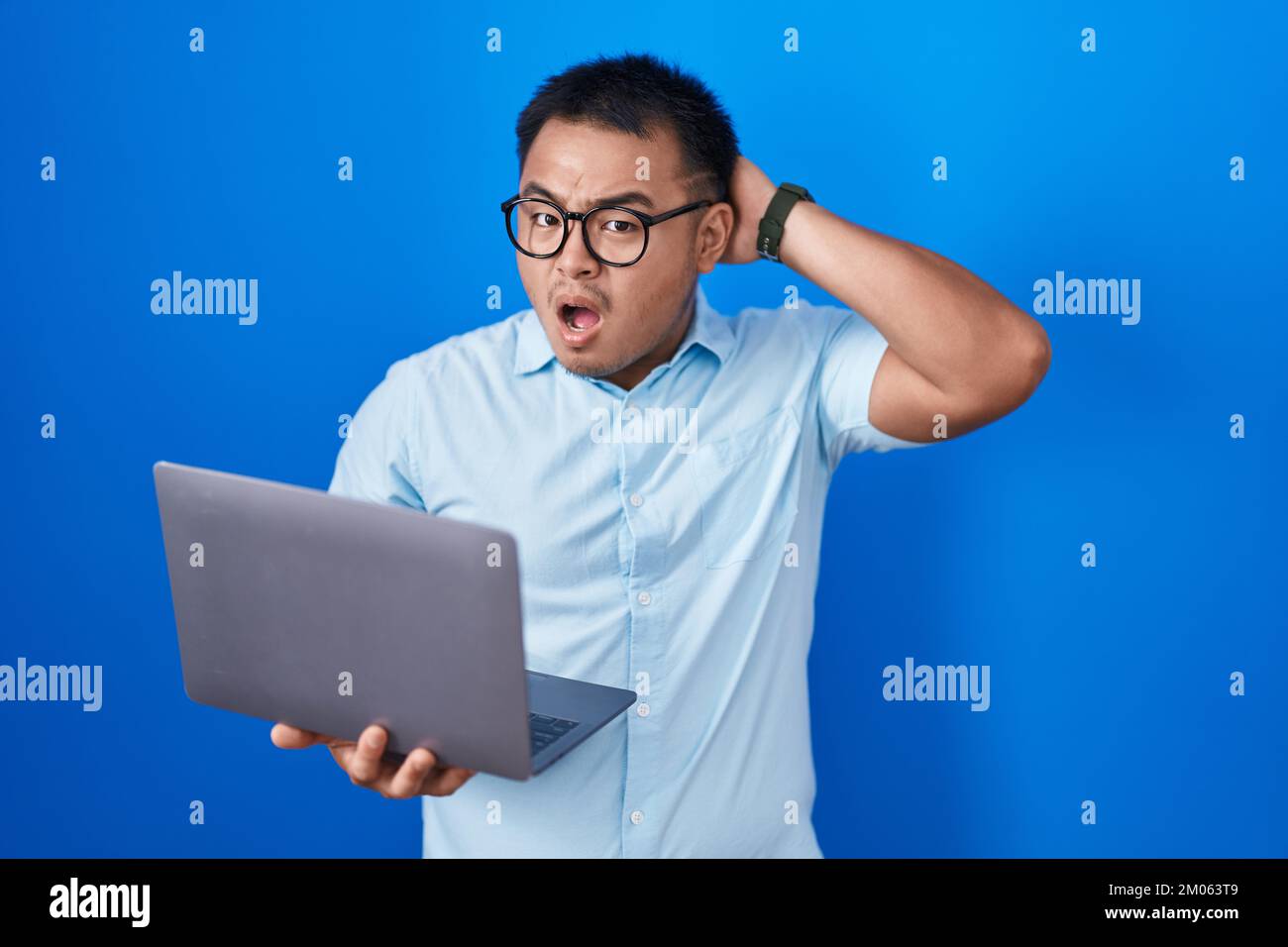 Chinese young man using computer laptop crazy and scared with hands on ...