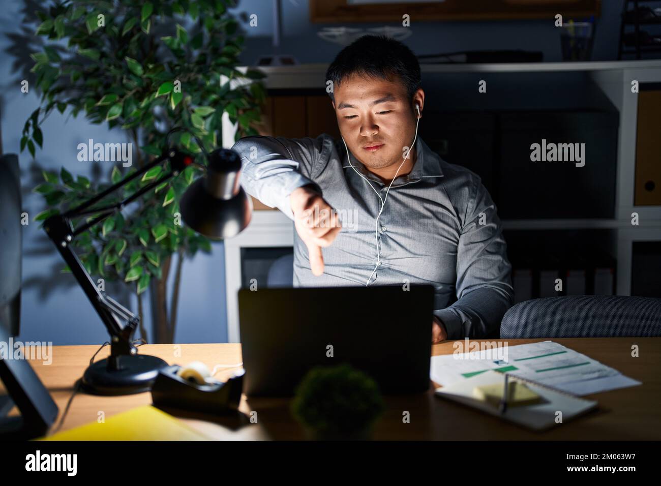 Young chinese man working using computer laptop at night looking ...