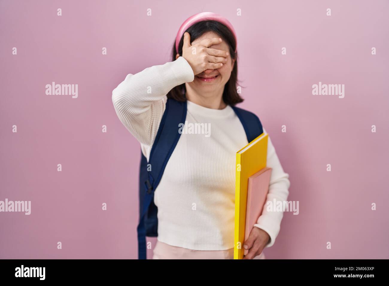 Woman with down syndrome wearing student backpack and holding books ...