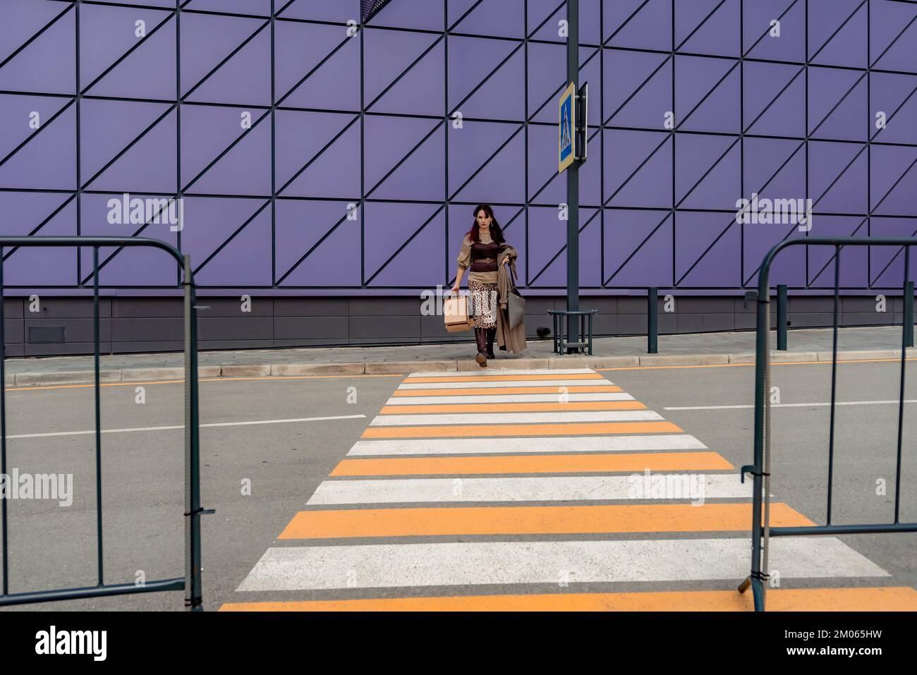 A beautiful girl with shopping bags is walking along a pedestrian ...