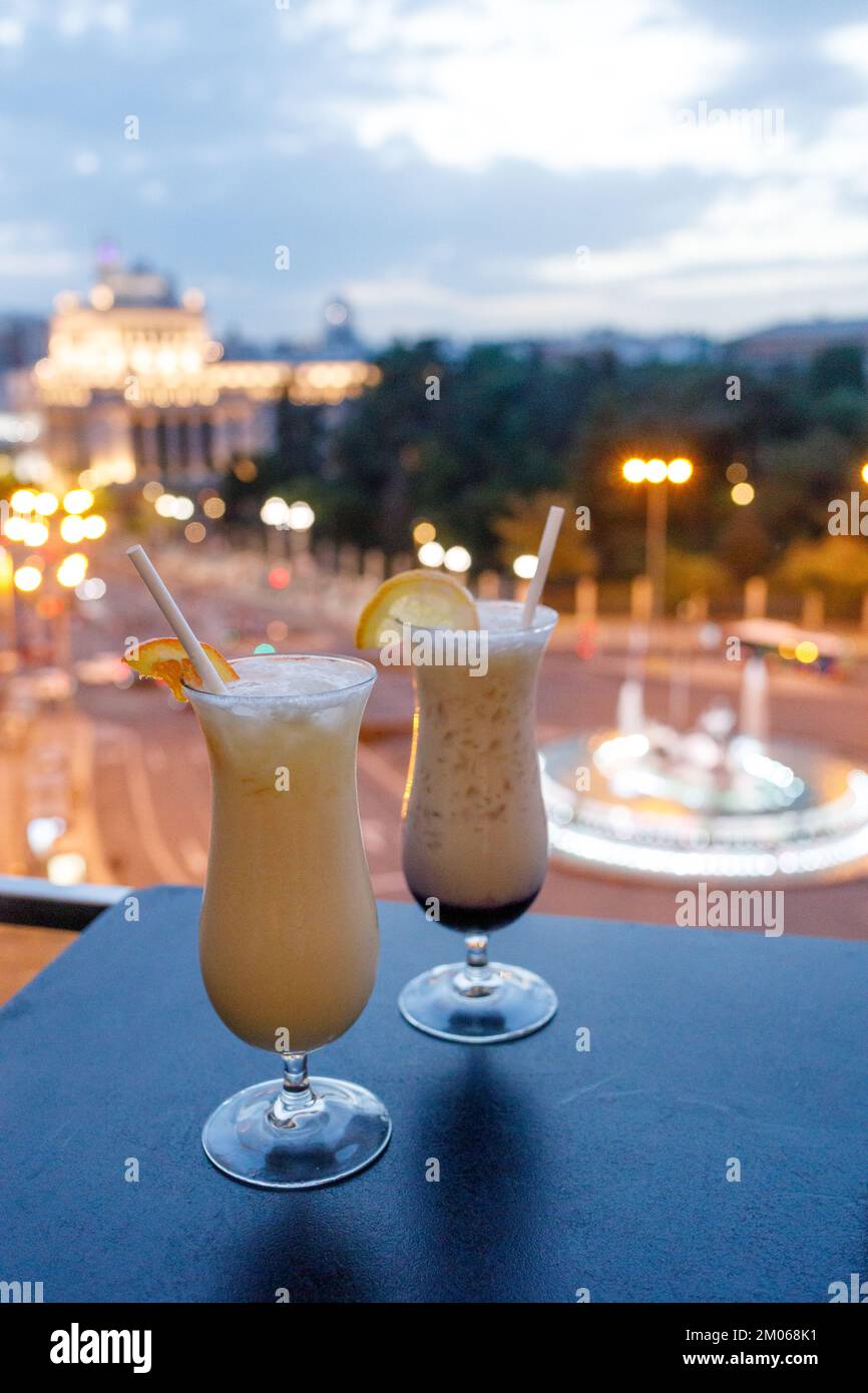 Cocktails with a straw and a slice of lemon on a glass. Blurred city ...