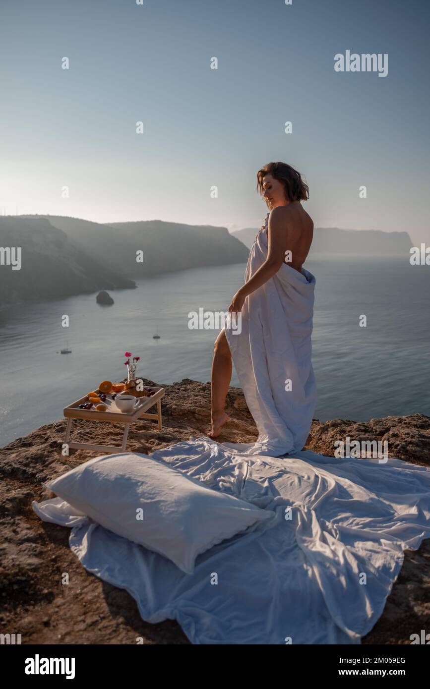 Woman wake up in bed wuth duvet and pillow over nature sea background ...