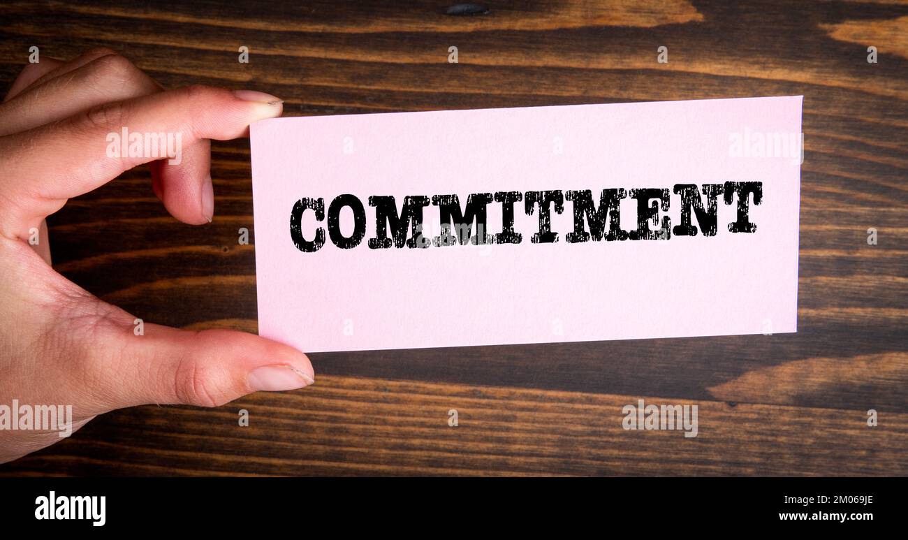Commitment. Text on a pink piece of paper. Wood texture background ...