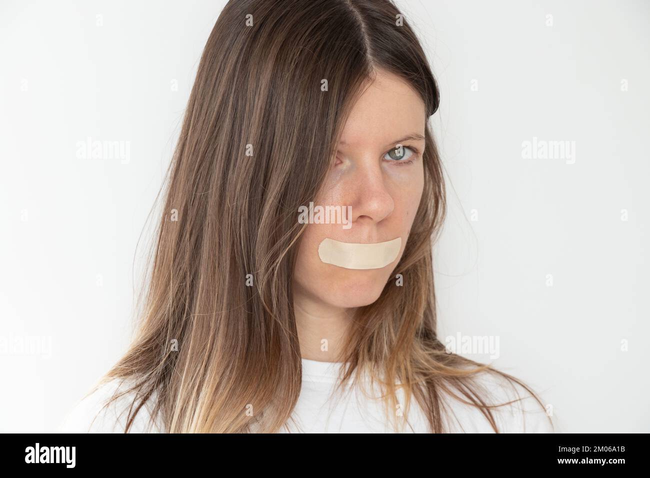 Girl with her mouth sealed with duct tape over isolated background ,be ...