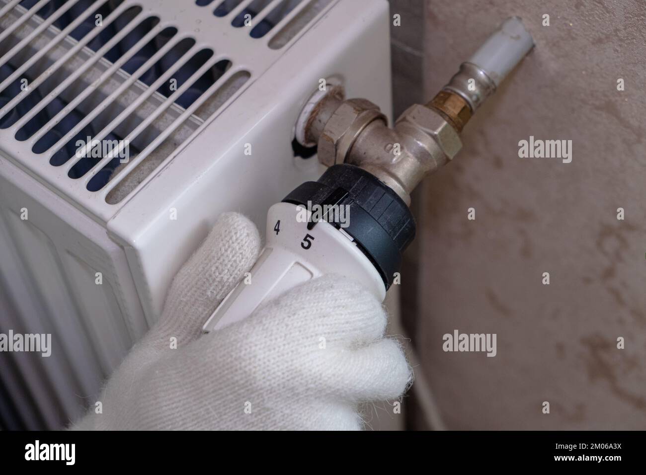 a hand in a glove turns the heating regulator on the radiator. increase ...