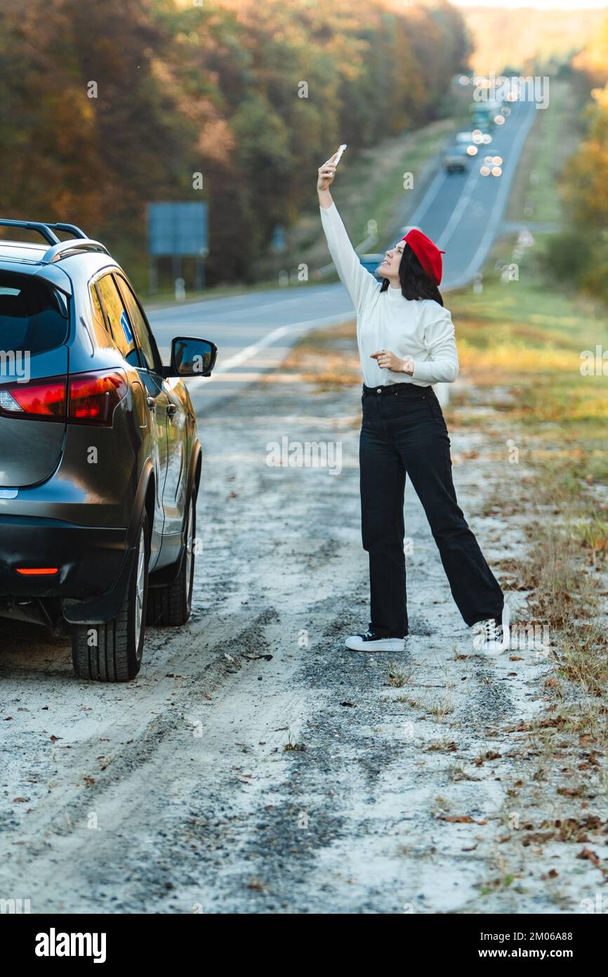 female driver is trying to catch network on her phone near car Stock ...