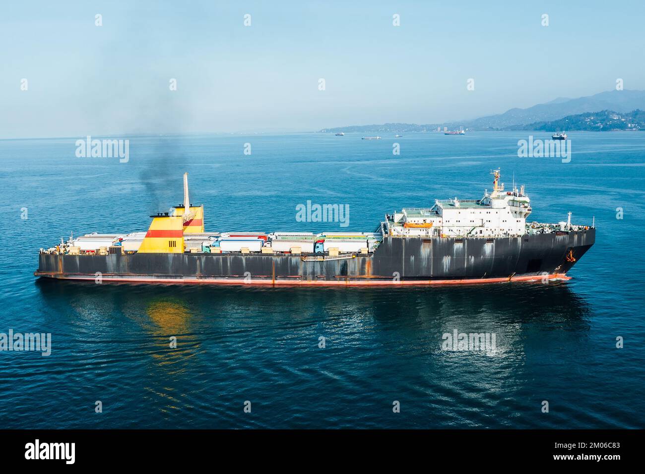 Freight cargo ship with trucks and containers in sea, aerial view from ...