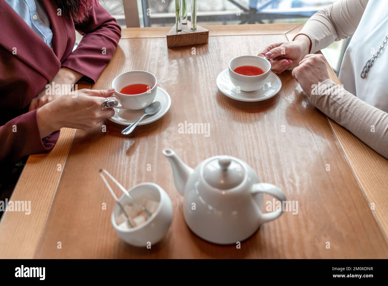Cups of black tea in the hands of men and women. on a wooden background ...