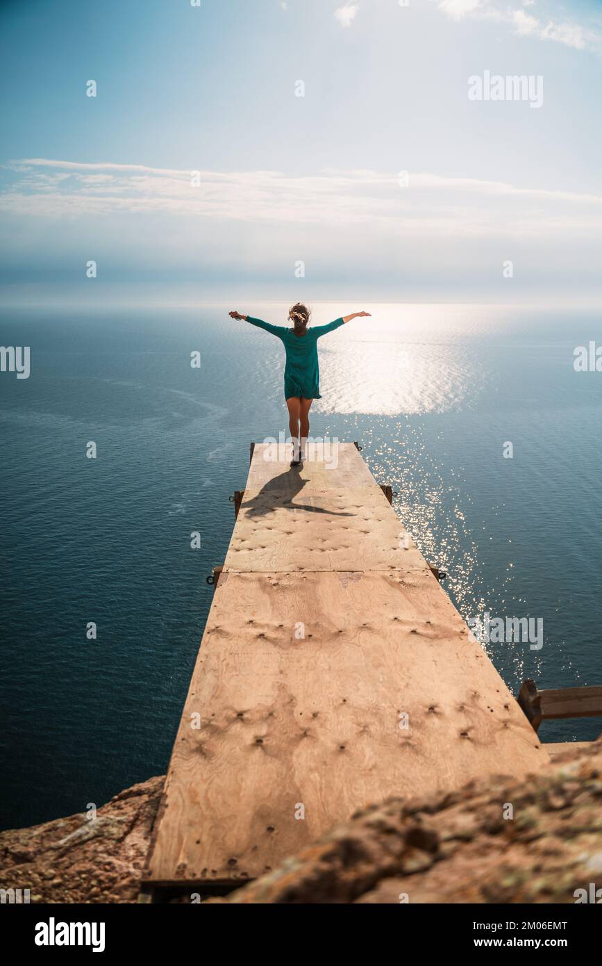 A girl sits on a wooden springboard for jumping with a rope. In a dark ...
