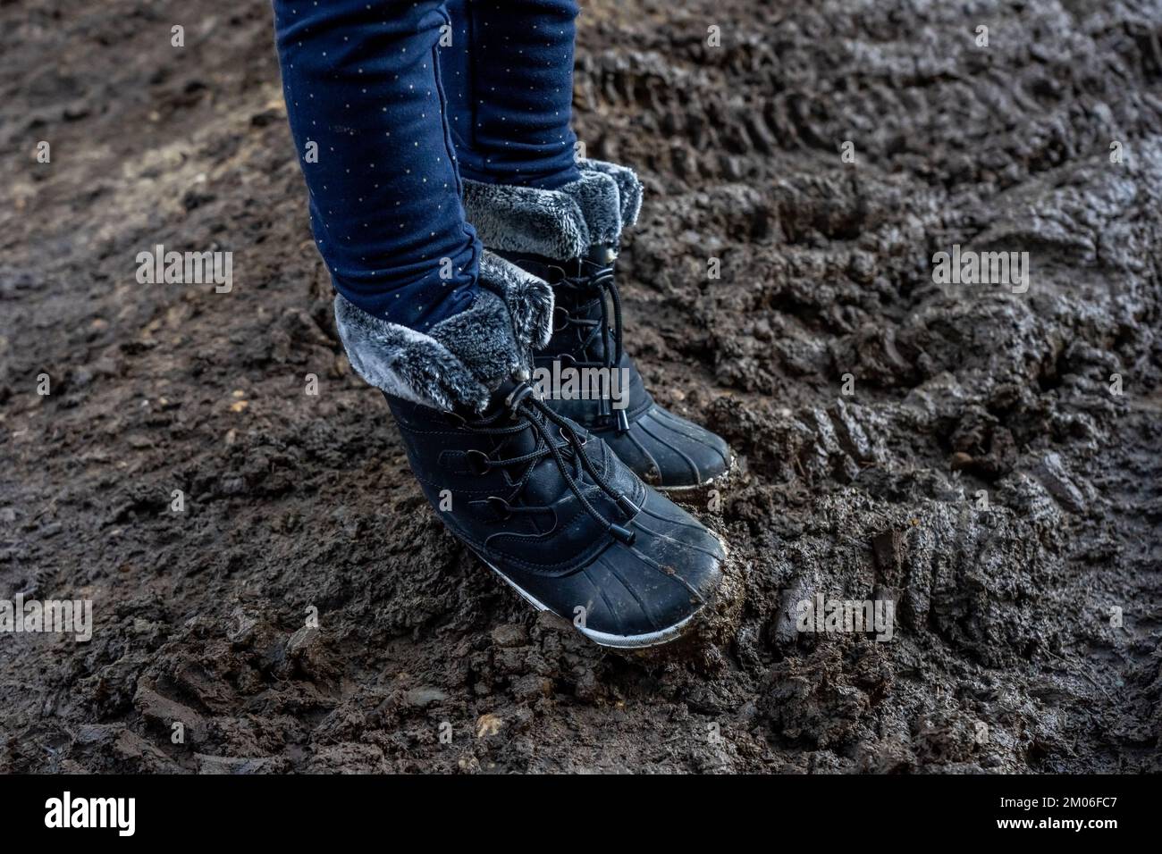 Child's feet in dirty stained boots, muddy background. Dirty in the mud ...