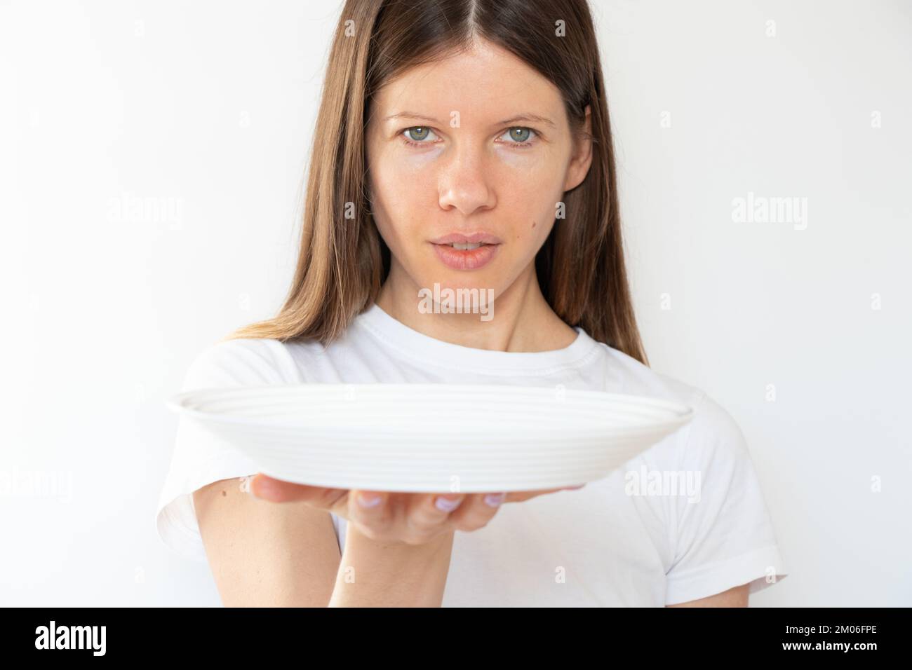 The girl is holding an empty white plate on a white background, the ...