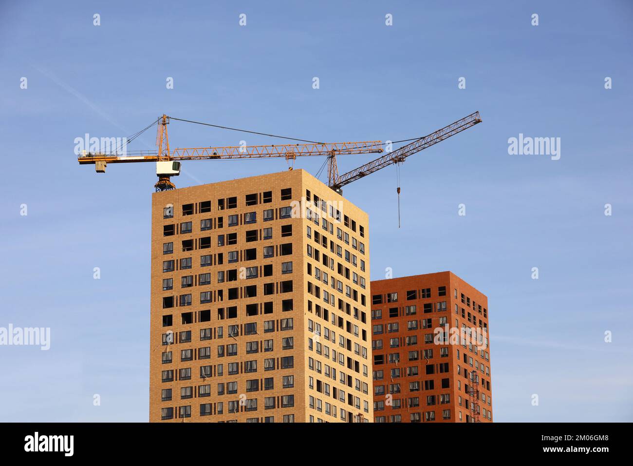 Tower cranes and unfinished buildings on background of blue sky ...