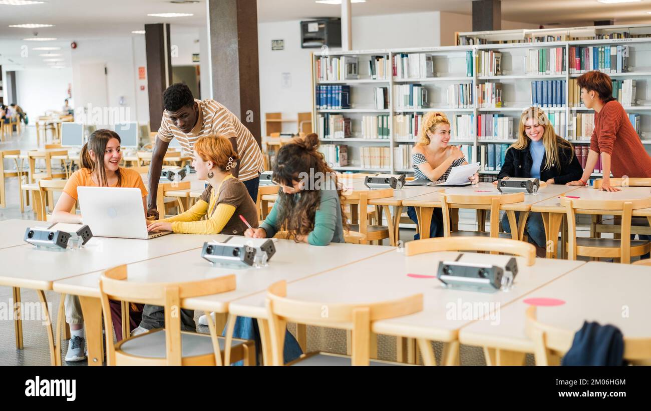 Group of students studying in the university library together and ...