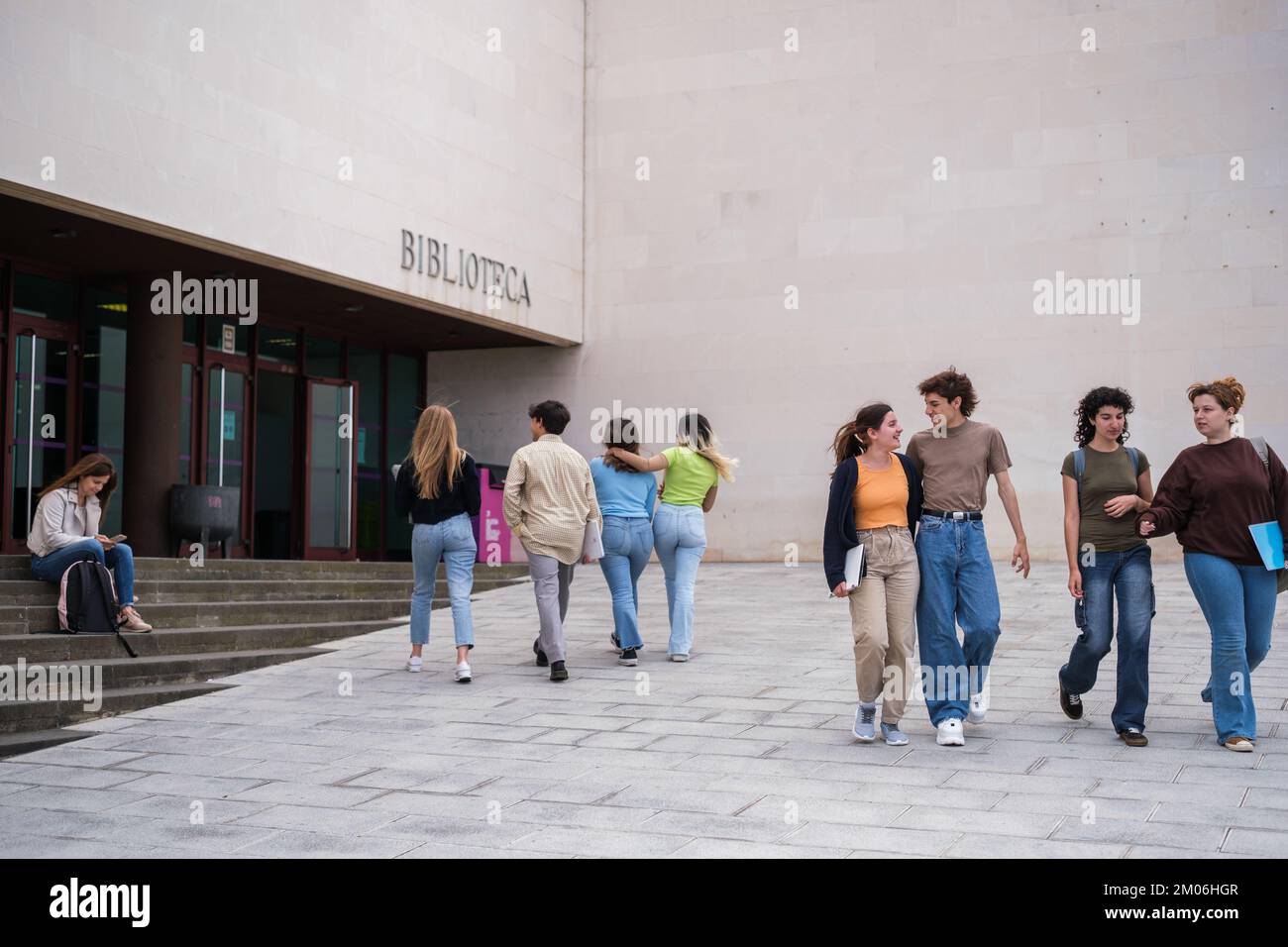 Group of students entering the library while other classmates have ...