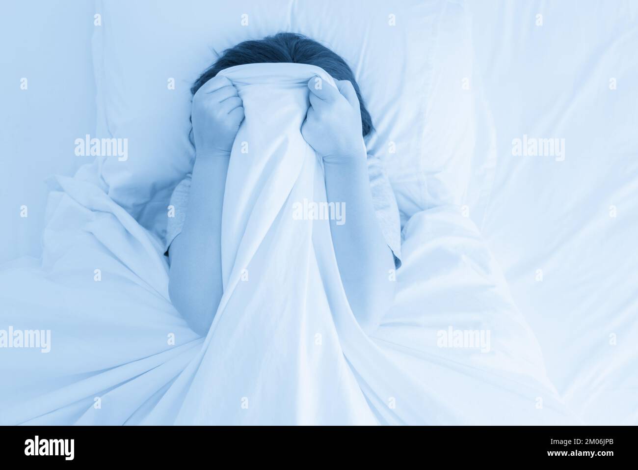 young woman laying in bed hiding her face Stock Photo - Alamy