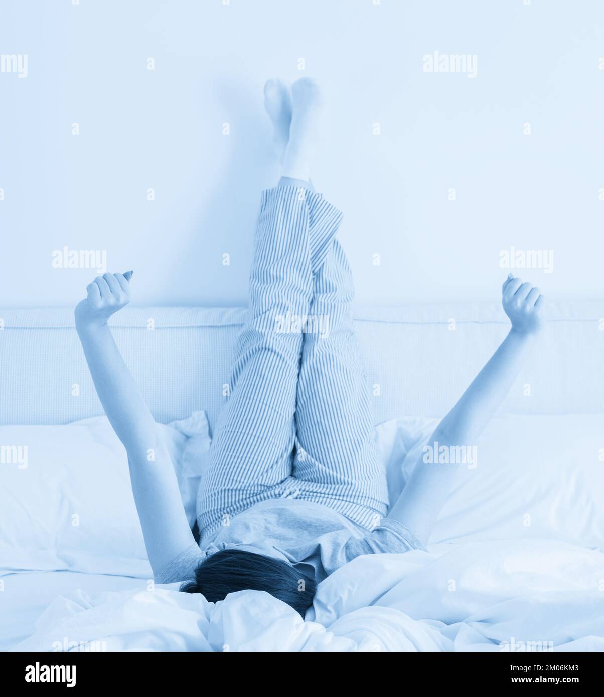 Yong woman in bed with legs up high against wall Stock Photo - Alamy