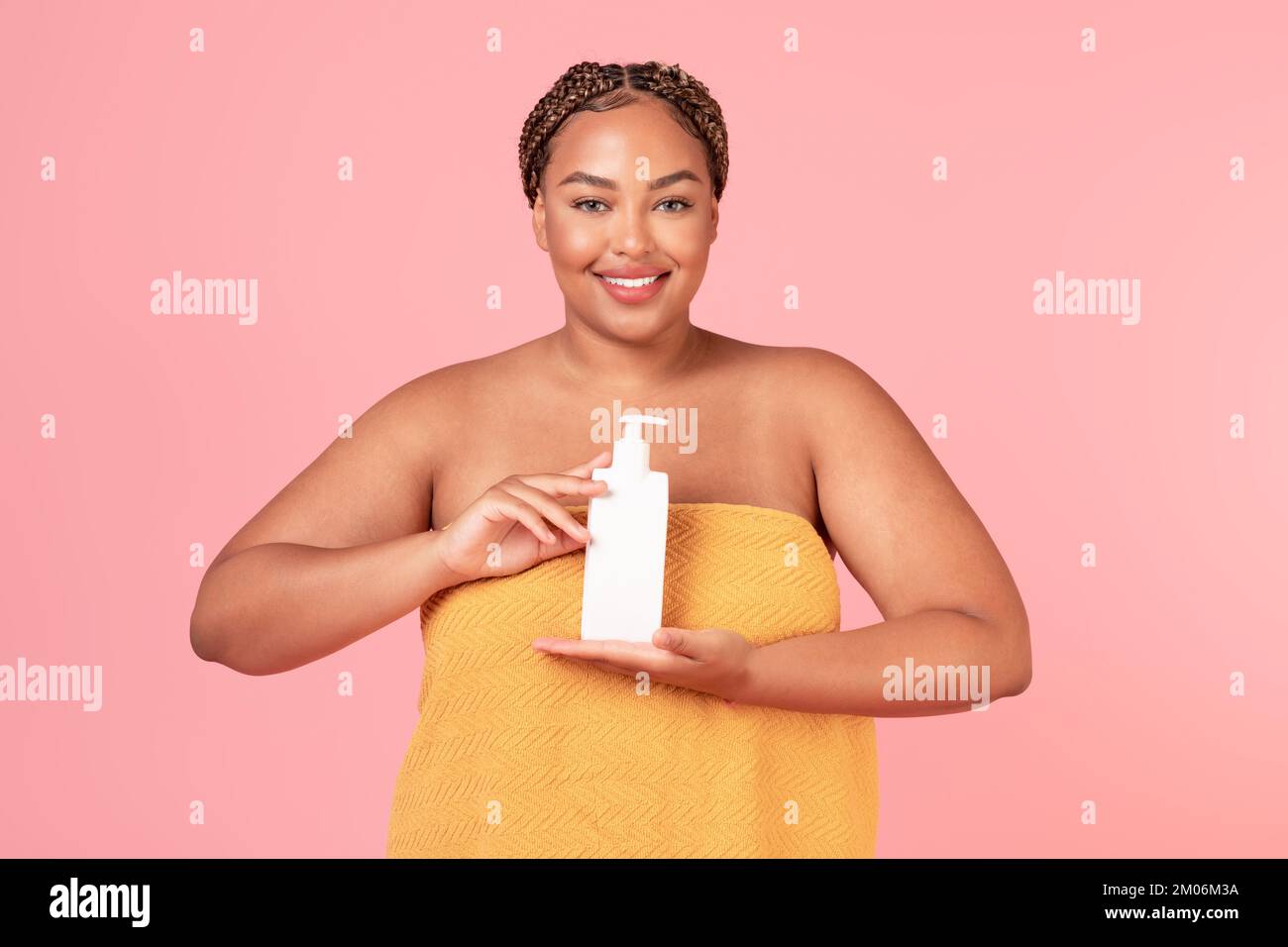 Beautiful black obese woman wrapped in towel holding bottle with ...