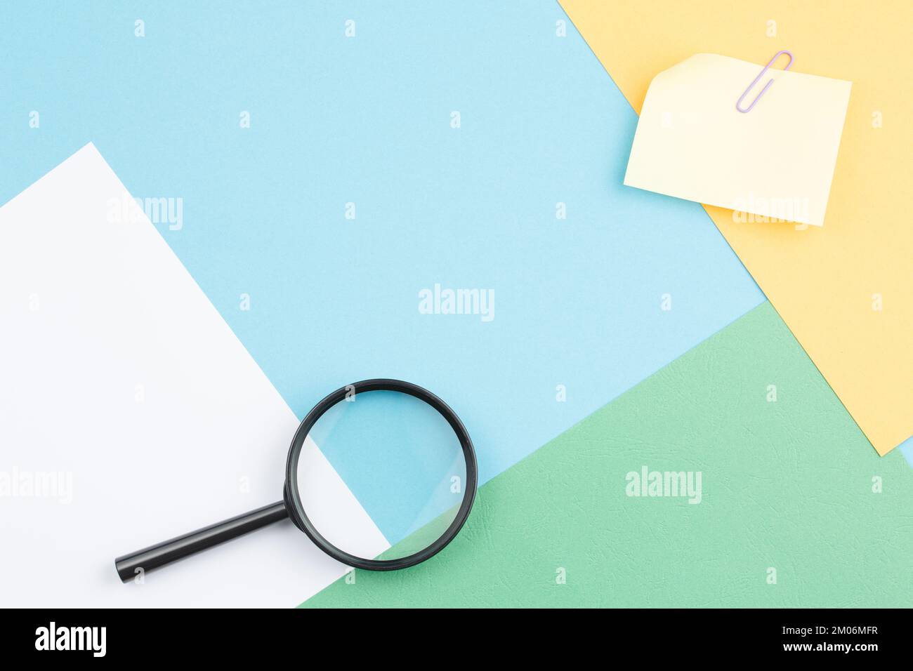 Colored paper background with magnifying glass Stock Photo - Alamy
