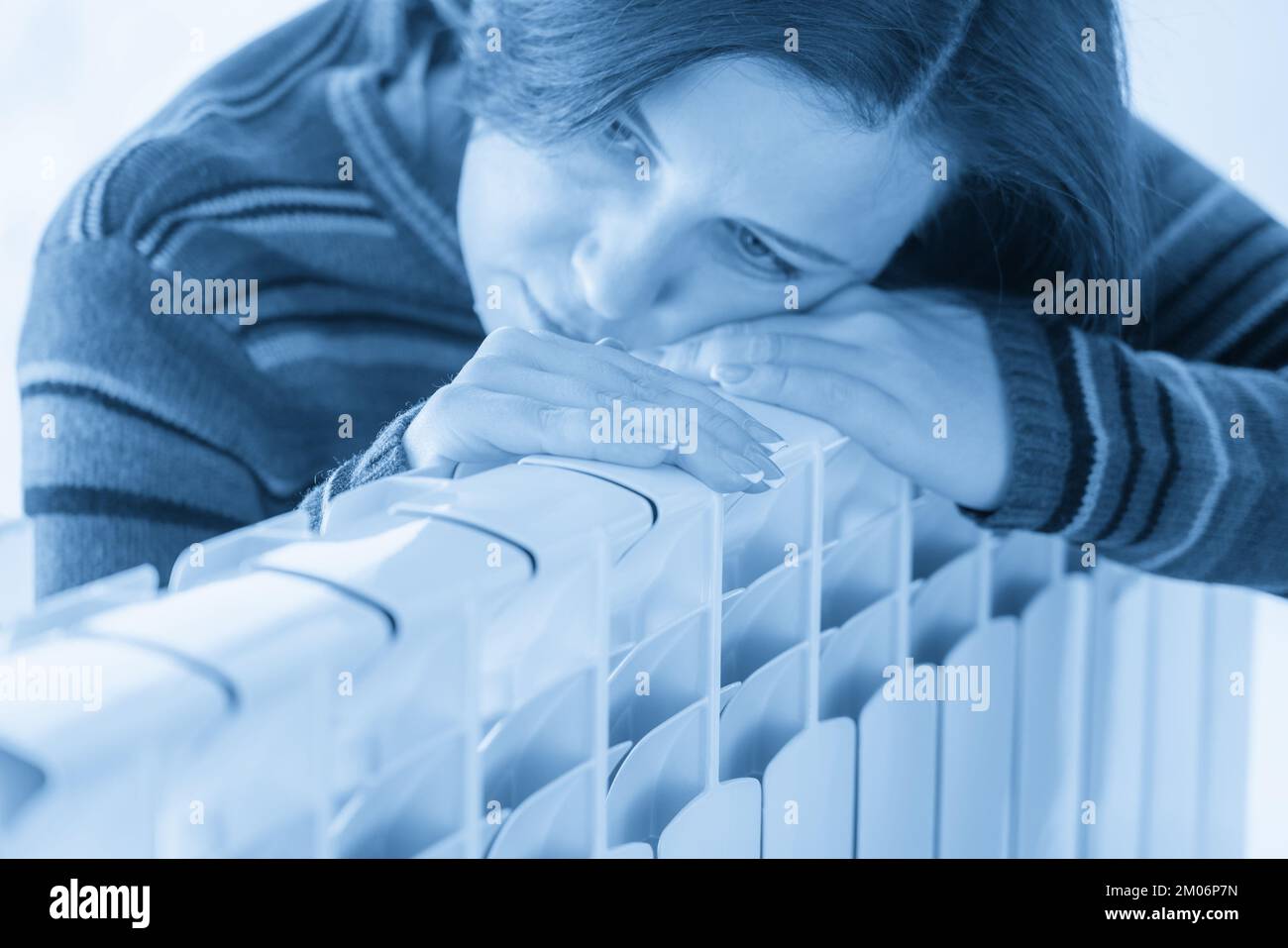 Woman wearing pullover sitting near heater radiator and hugs it Stock ...