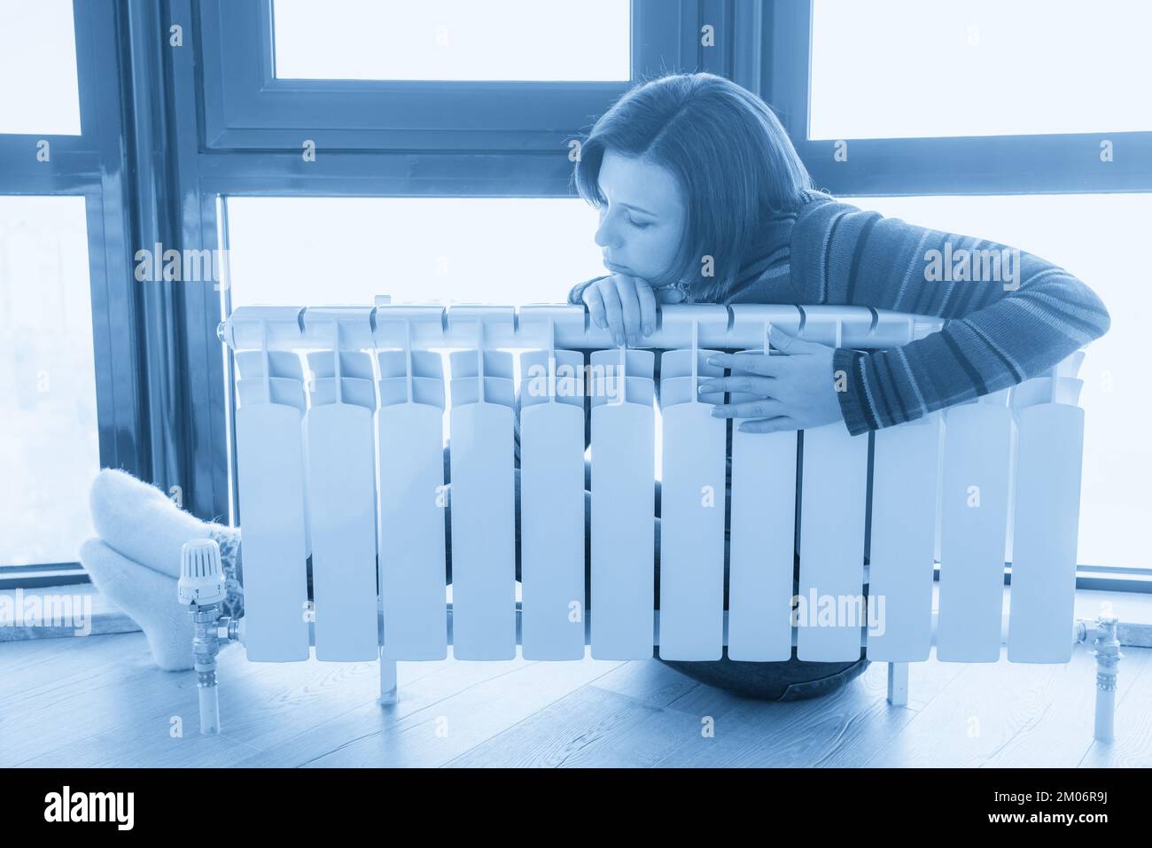 Woman wearing pullover sitting near heater radiator and hugs it Stock ...