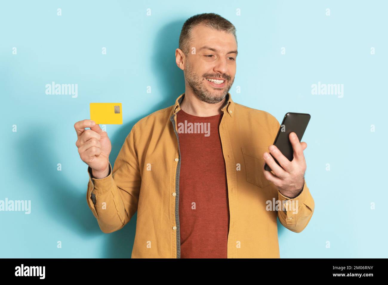 Mobile shopping concept. Happy mature man using smartphone and credit ...