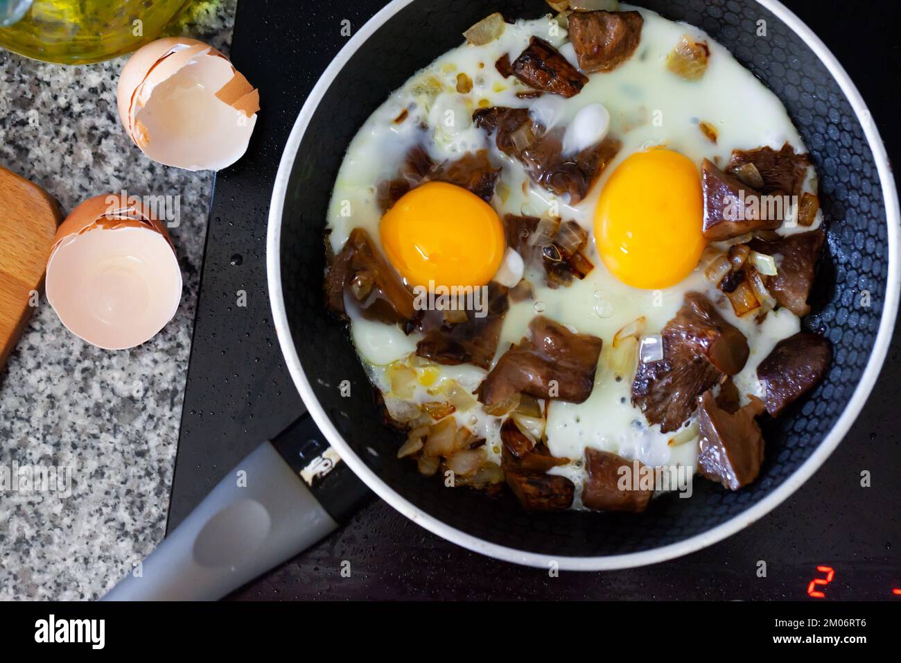 Eggs with mushrooms frying in pan in kitchen Stock Photo - Alamy
