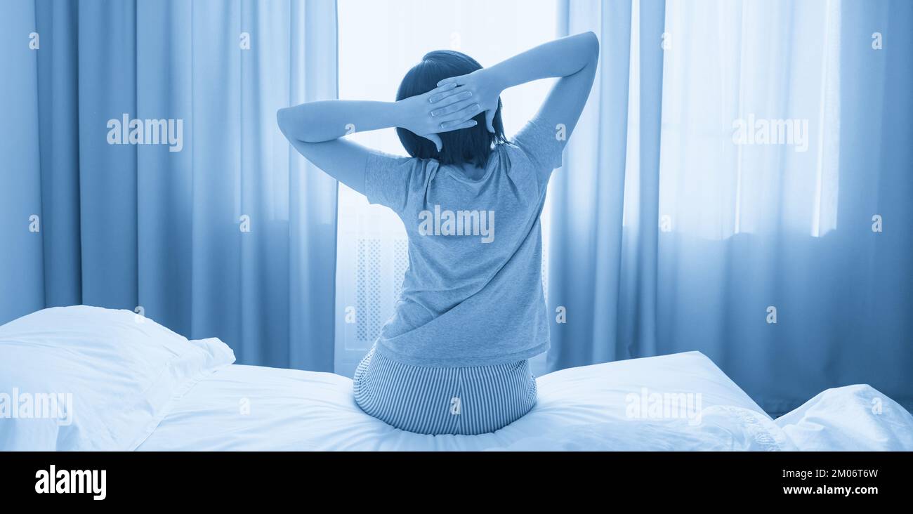 Pano of woman stretching in bed after wake up, back view Stock Photo ...