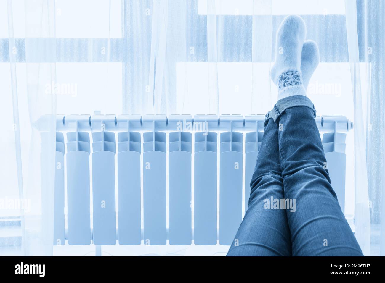 Woman laying on floor with feet raised up on radiator for warming up ...