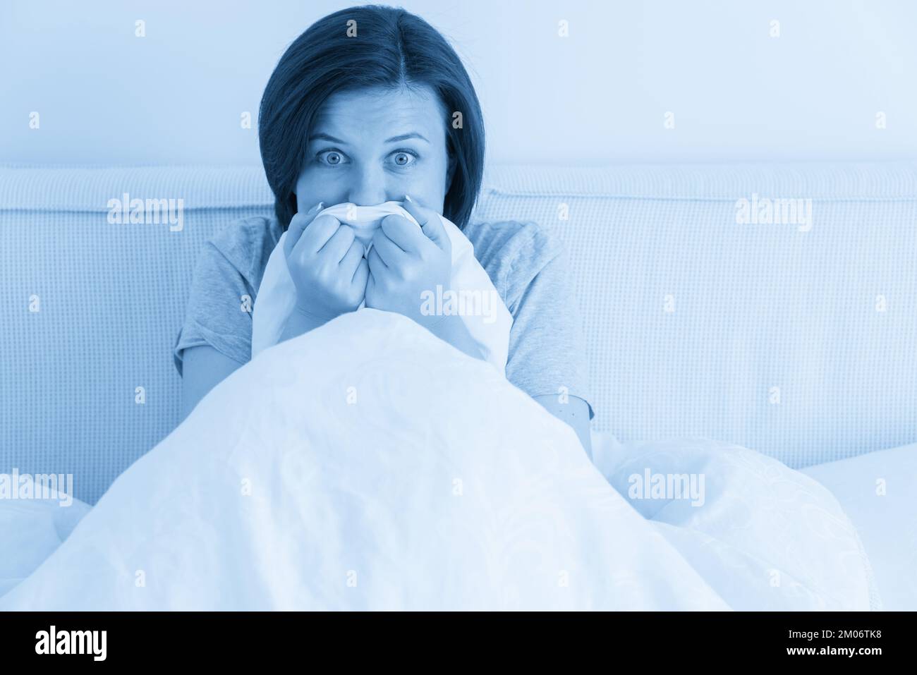 young woman sitting in bed and is scared and terrified Stock Photo - Alamy