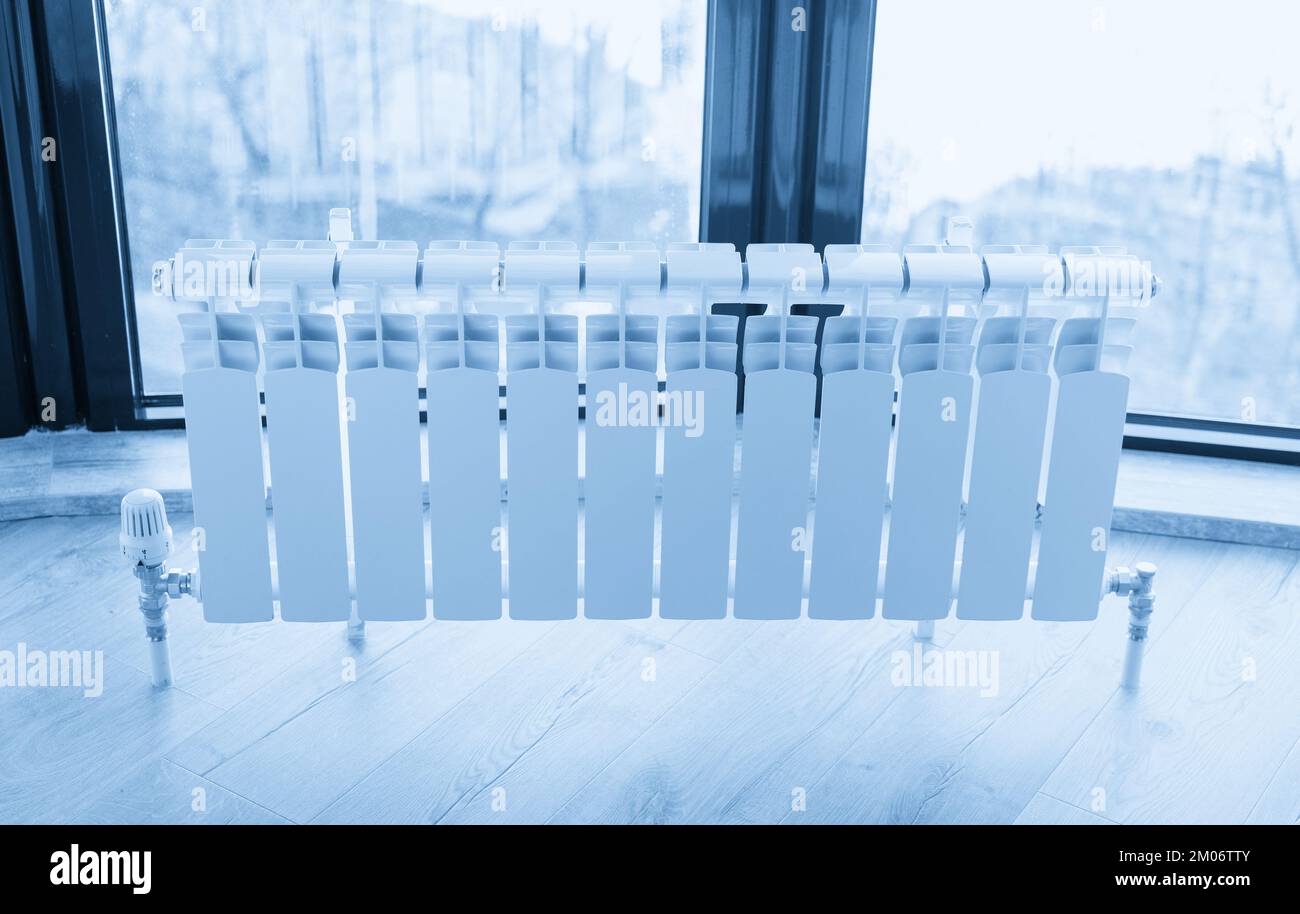 White big radiator with thermostat against window in modern room Stock ...