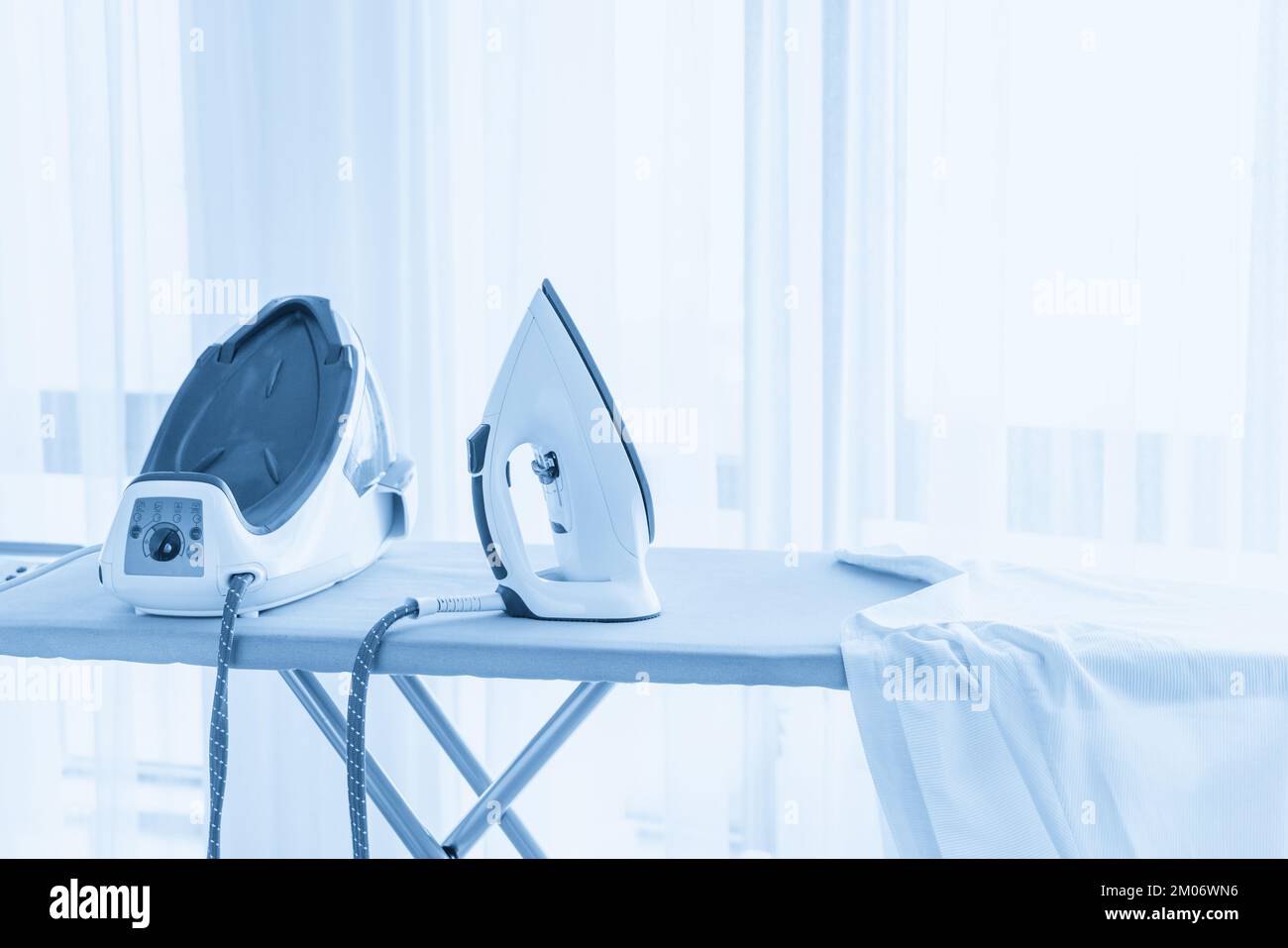 Steam iron standing on ironing board near window with copy space Stock ...