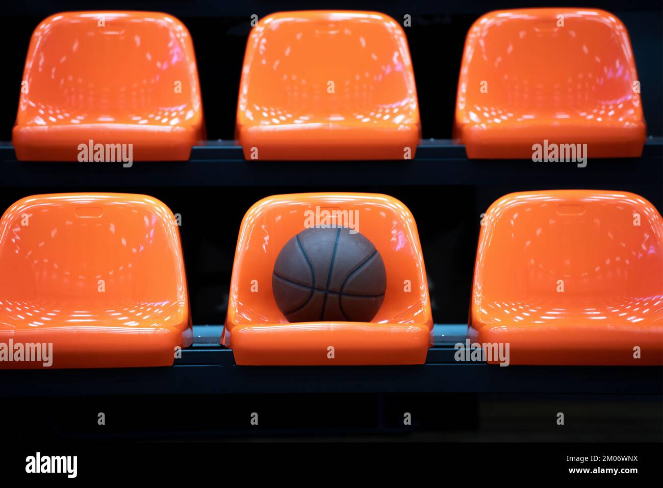 Brown basketball ball on orange bench in arena. Horizontal sport poster ...