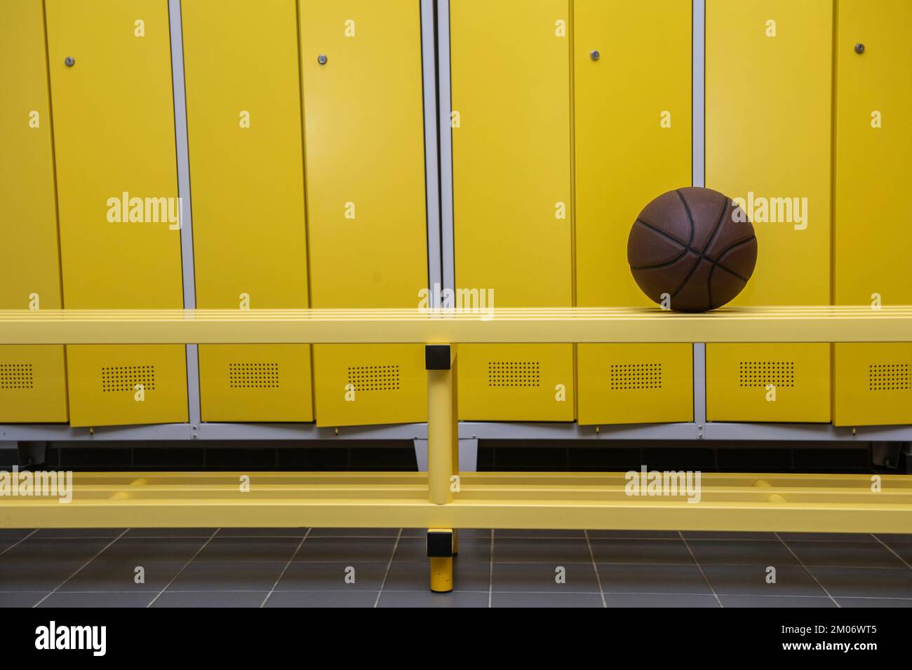 Brown basketball ball on yellow bench in locker room. Horizontal sport ...