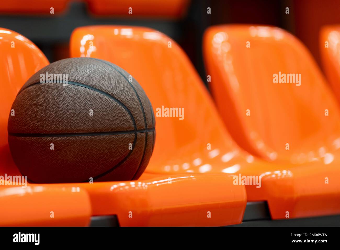 Brown basketball ball on orange bench in arena. Horizontal sport poster ...